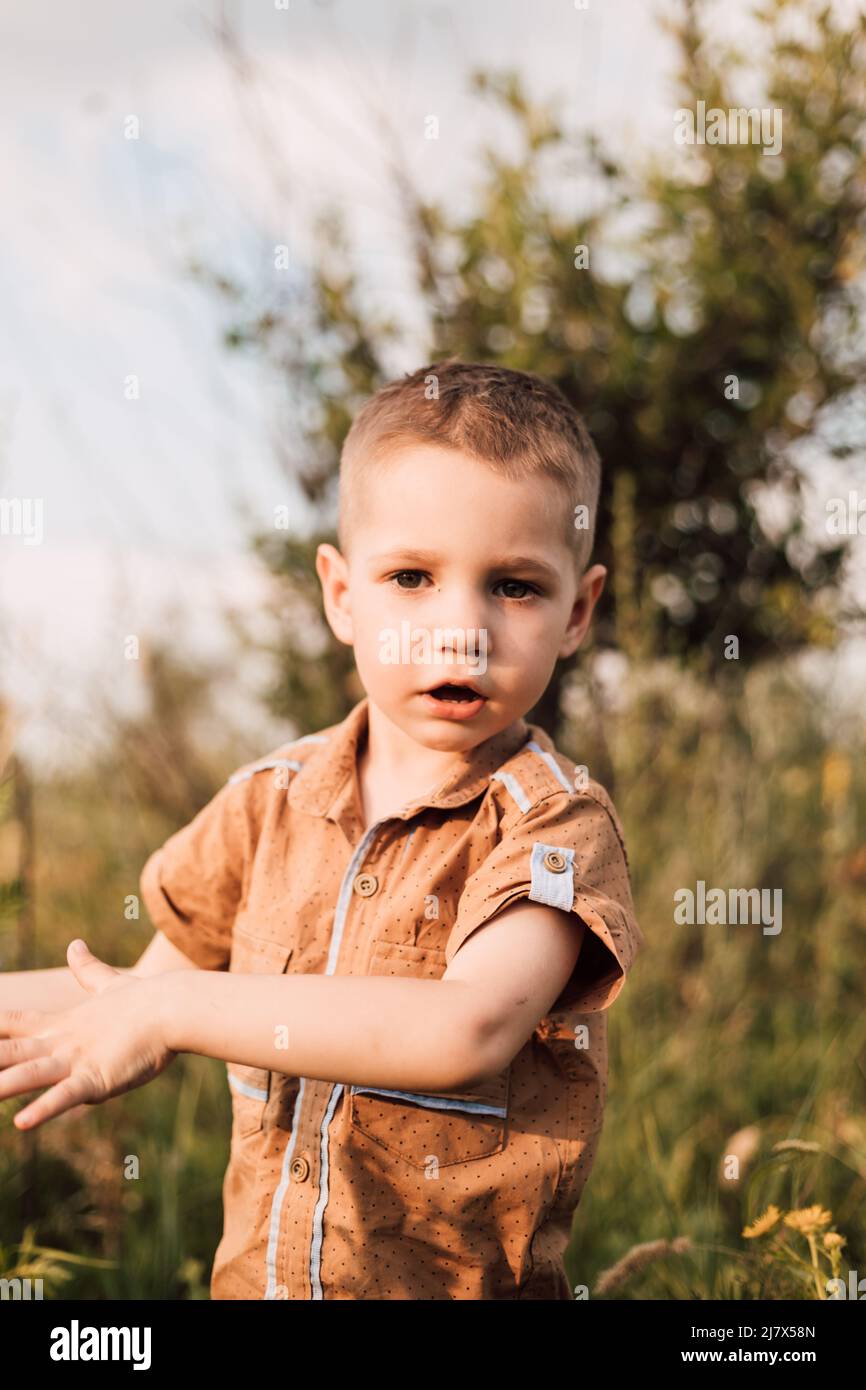 A little boy stands in nature and smiles Stock Photo - Alamy