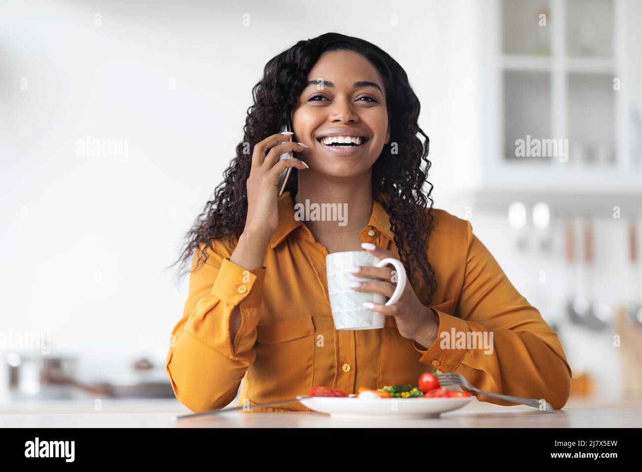 Cheerful black woman talking on phone while having breakfast Stock ...