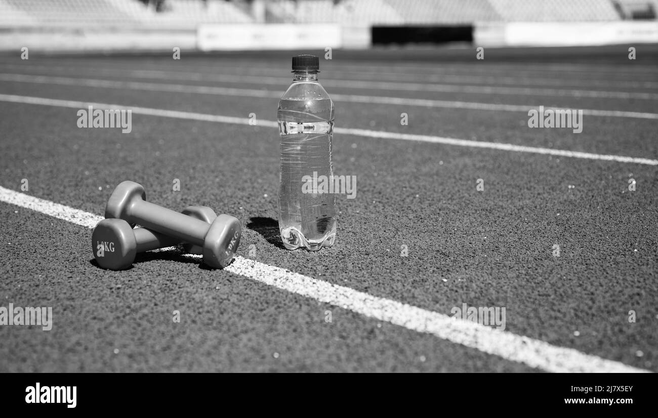 barbells and bottle on running track. sport tool and equipment ...