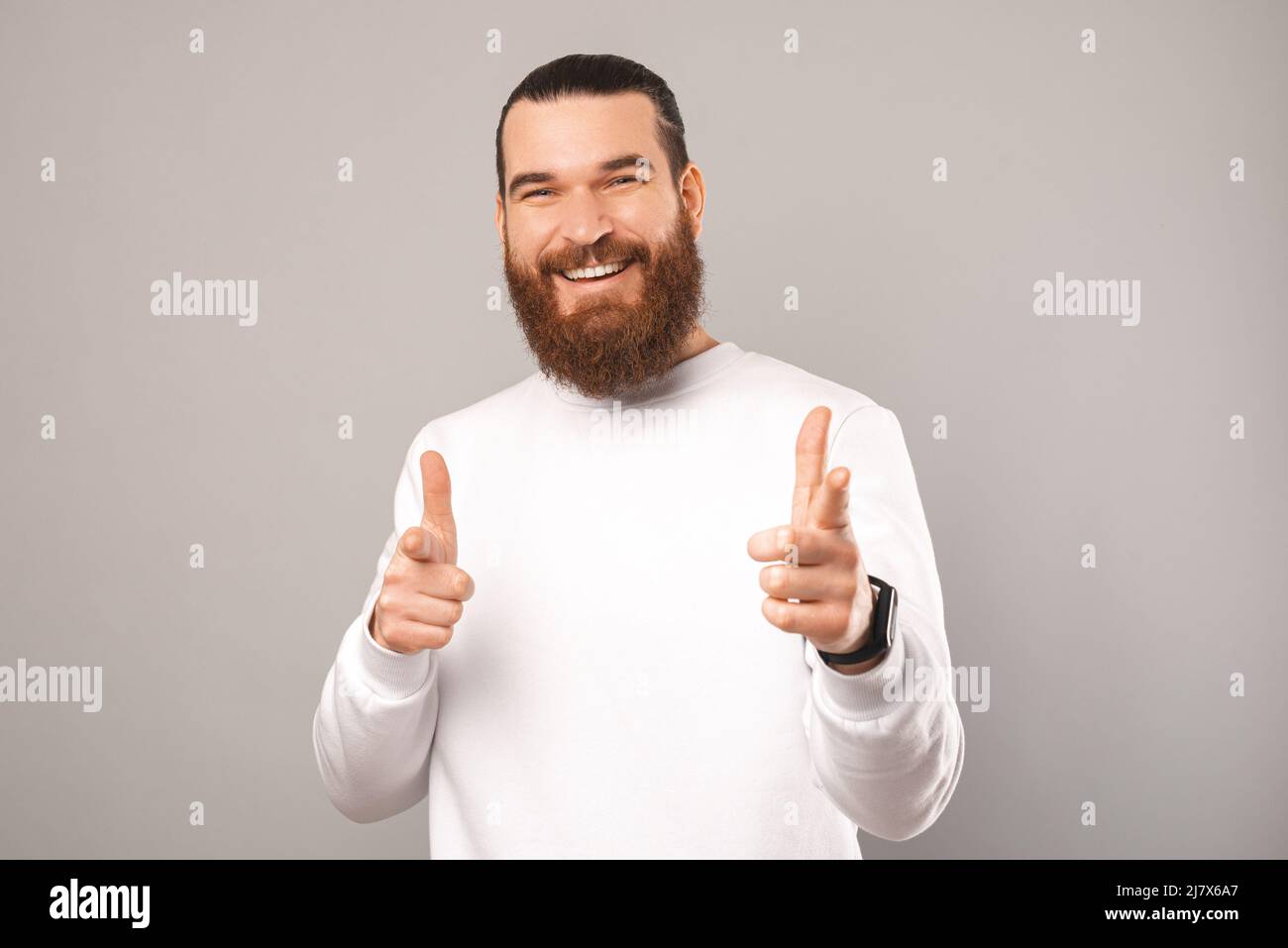 Smiling young man is pointing towards the camera for you in a studio ...