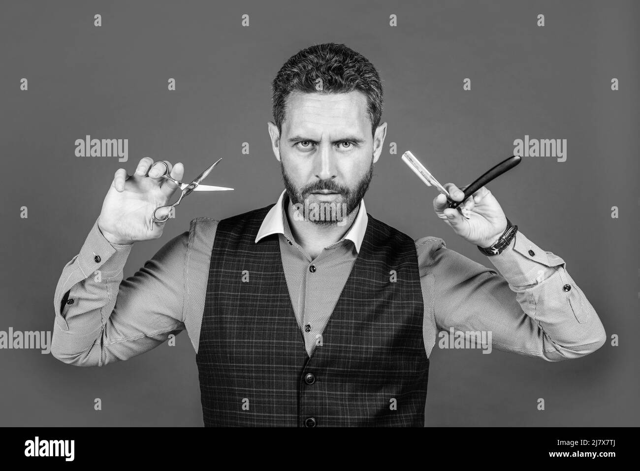 Handsome man with unshaven facial hair hold scissors and open razor ...