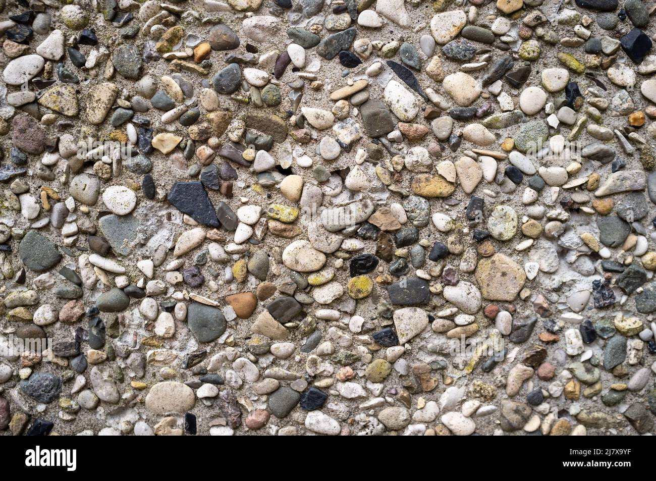 Wall of small stones in concrete, outdoors. Textured background. Copy ...
