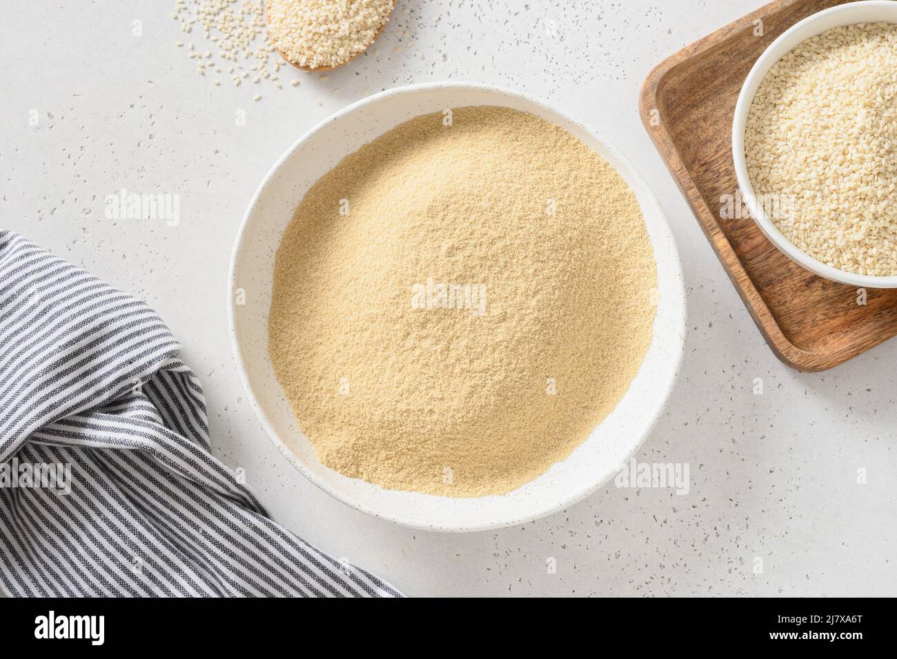 Sesame flour in bowl and organic sesame seeds on white background for ...