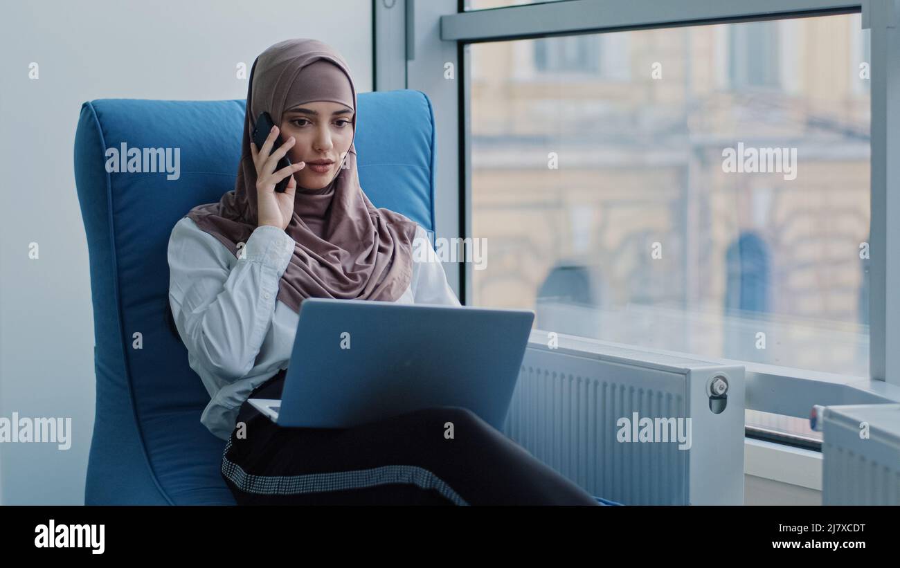 Thoughtful Arabic female manager in hijab sitting in comfortable ...
