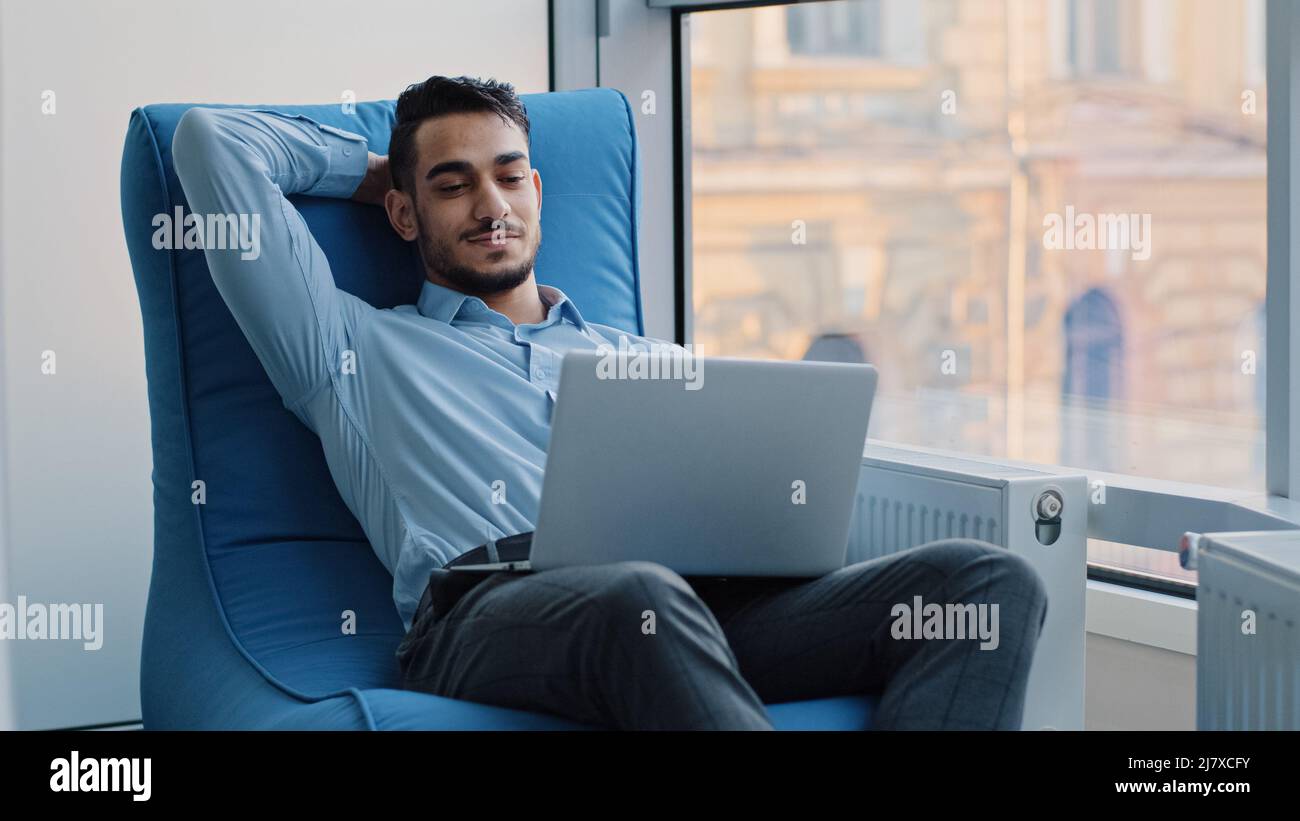 Relaxed happy Indian businessman student worker sits in comfortable ...