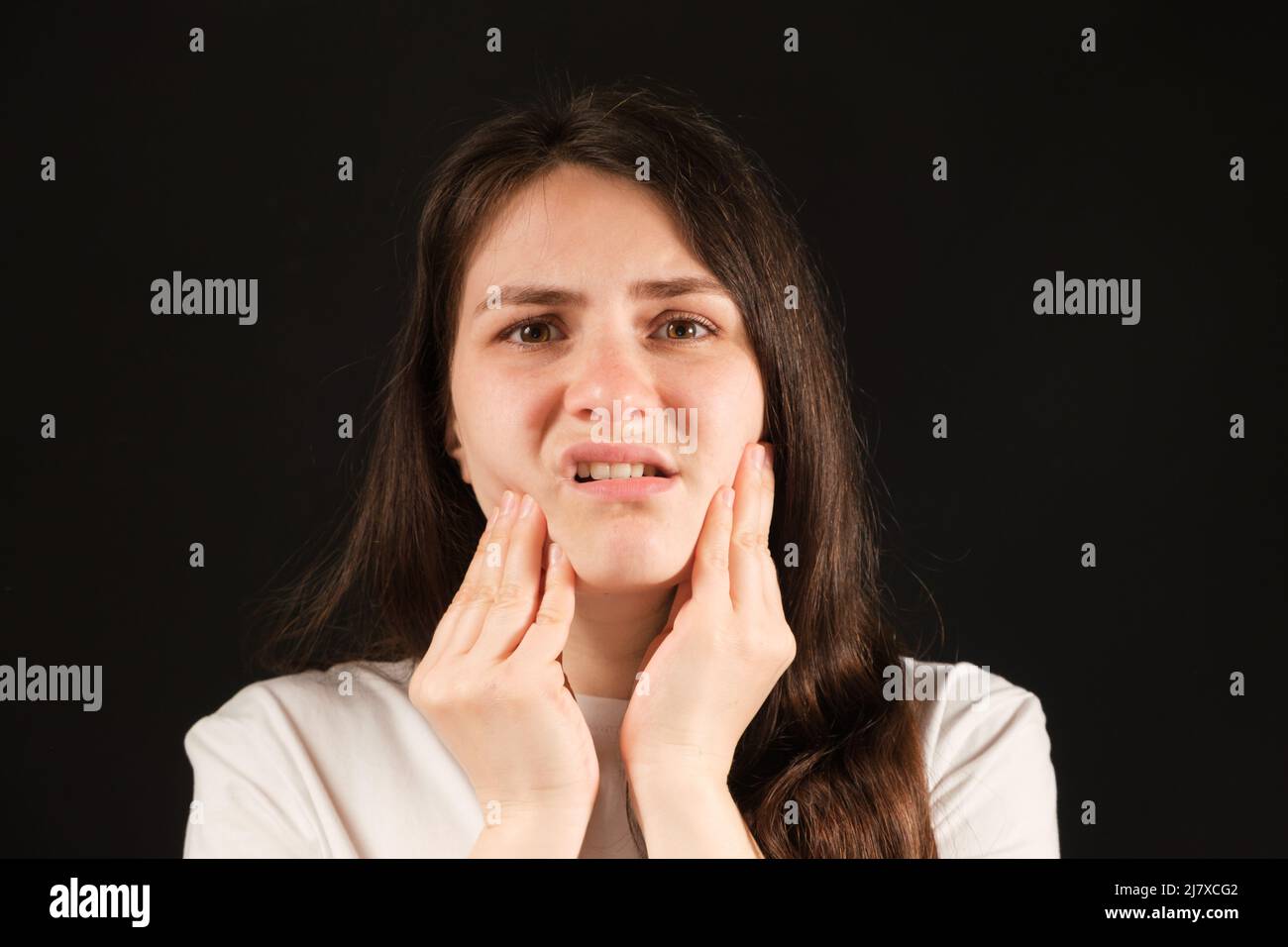 A woman holds her hands to a sore temporomandibular joint, dysfunction ...