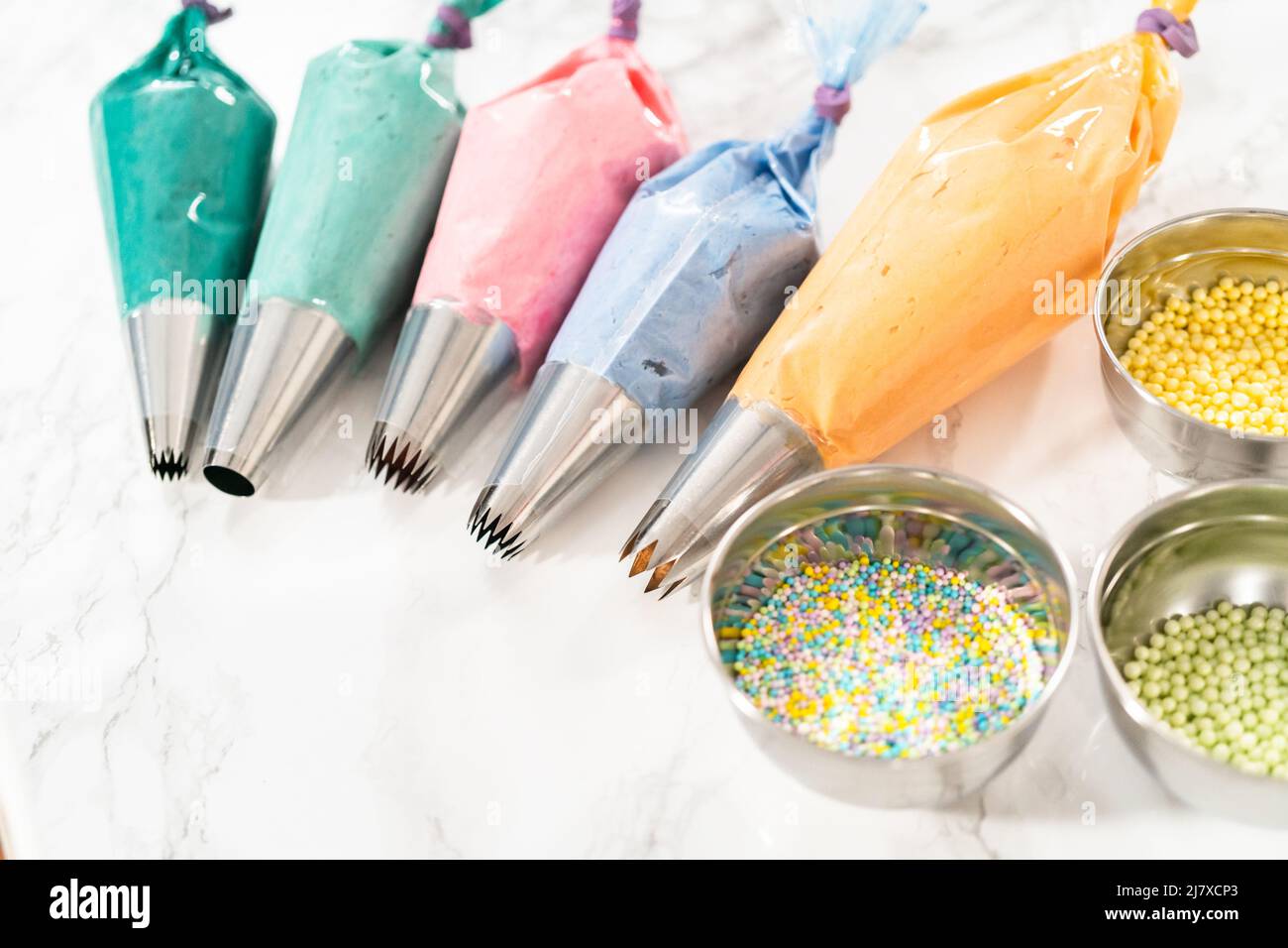 Piping bag with metal tips filled with colorful Italian buttercream ...