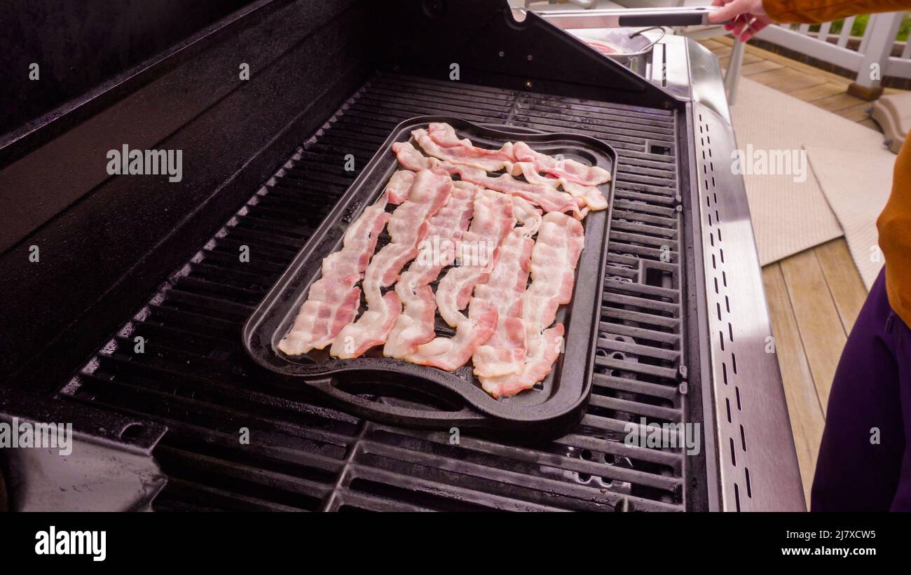 Cooking bacon stips on an outdoor gas grill Stock Photo - Alamy