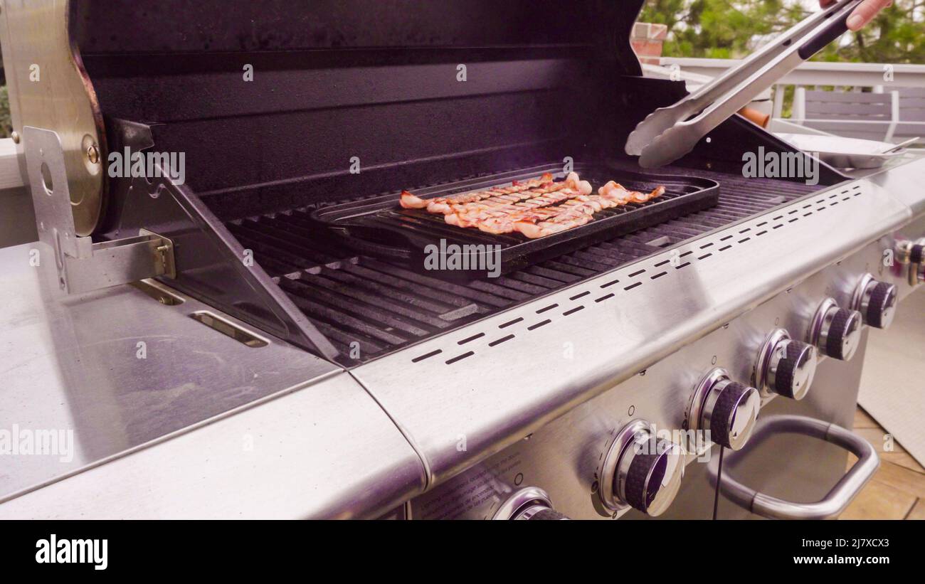 Cooking bacon stips on an outdoor gas grill Stock Photo - Alamy