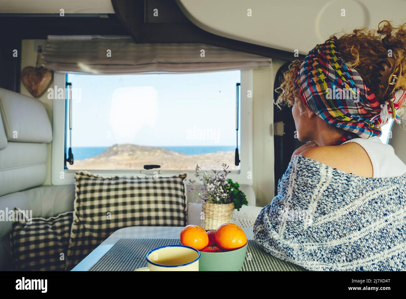 Back view of a woman looking outside the window inside a camper van ...