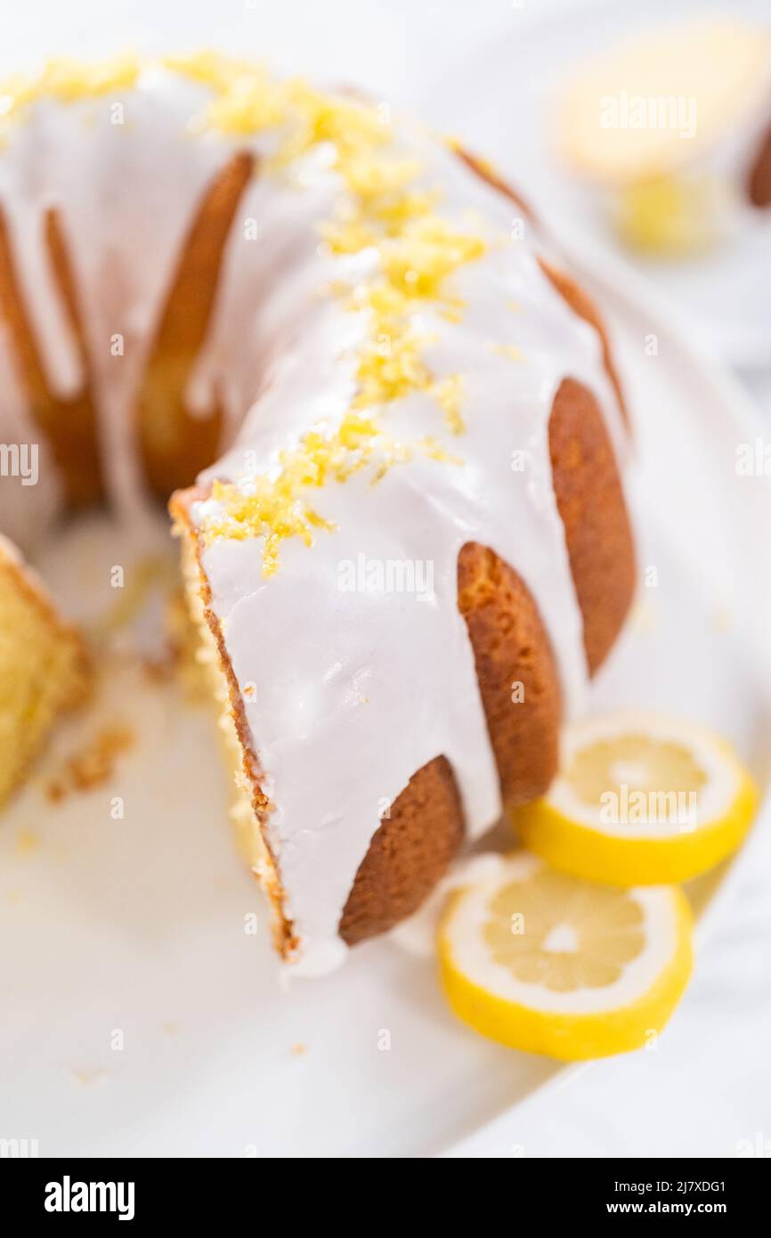Sliced lemon bundt cake decorated with lemon zest on a cake stand Stock ...