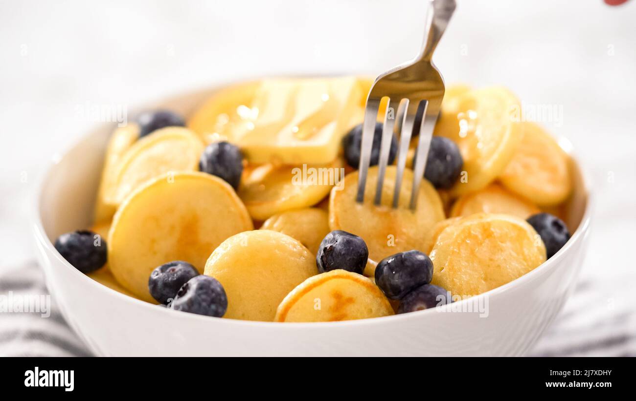Step by step. Freshly made mini pancake cereal with fresh blueberries in a white bowl Stock ...