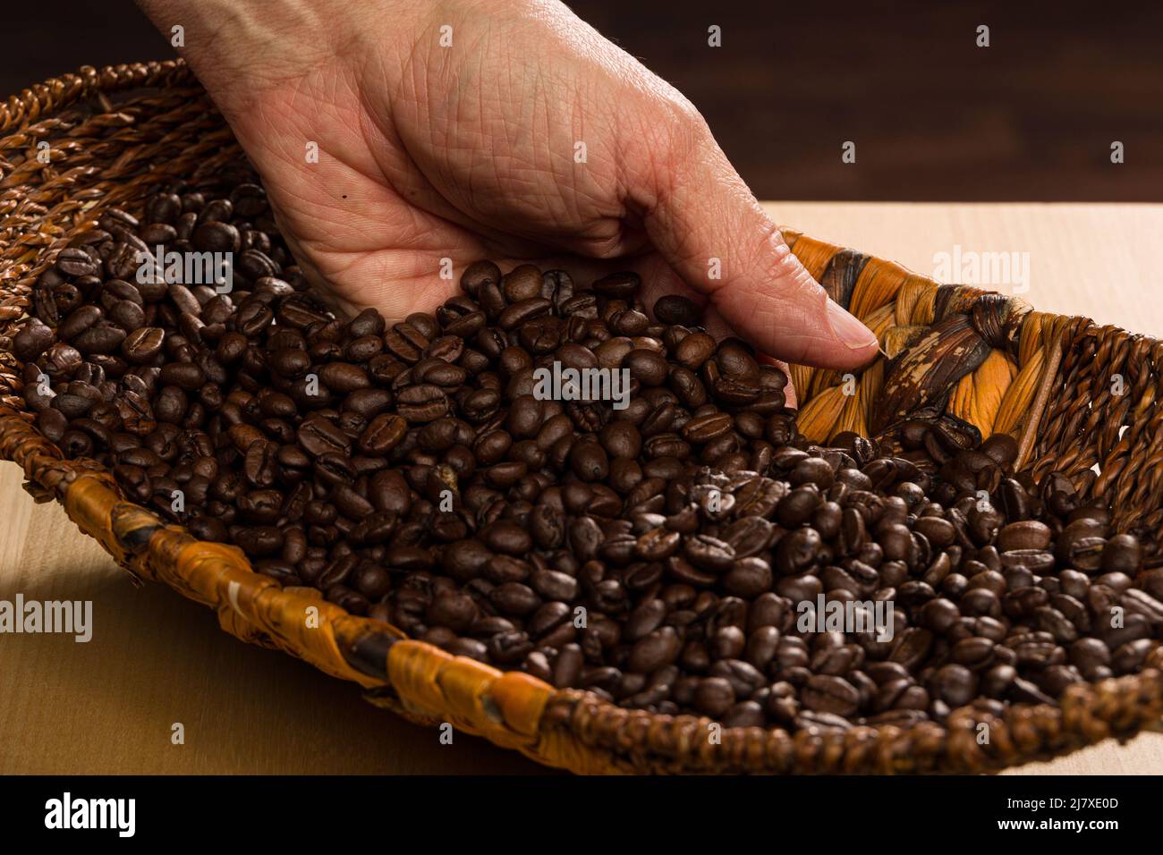 a hand grabs freshly roasted coffee beans out of a basket Stock Photo ...
