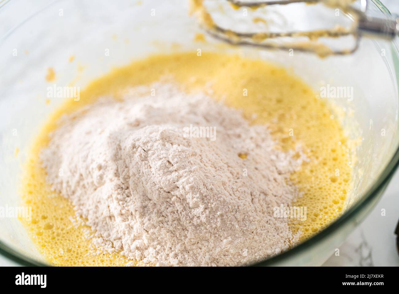 Mixing ingredients with a hand mixer in a large mixing bowl to bake ...