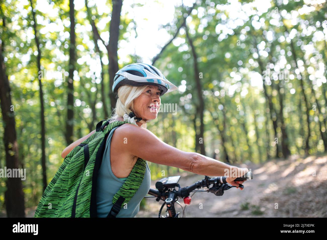 Active senior woman biker pushing bike outdoors in forest Stock Photo ...