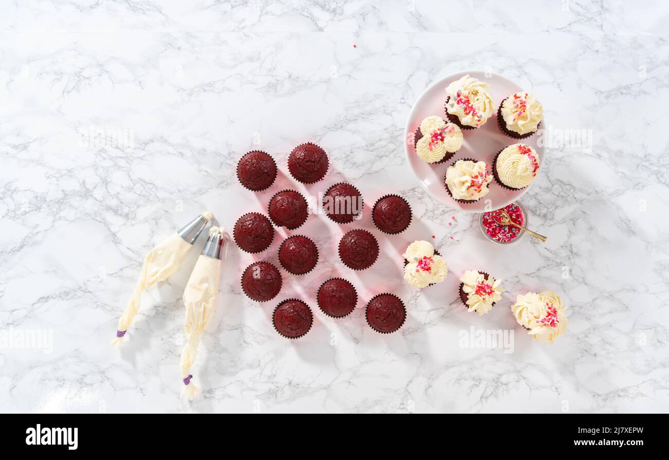 Flat lay. Piping white chocolate ganache frosting on top of red velvet ...