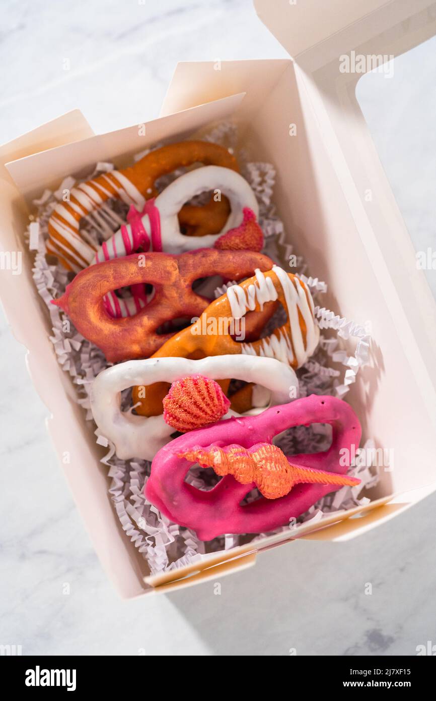 Packaging gourmet chocolate-covered pretzel twists into a white paper ...