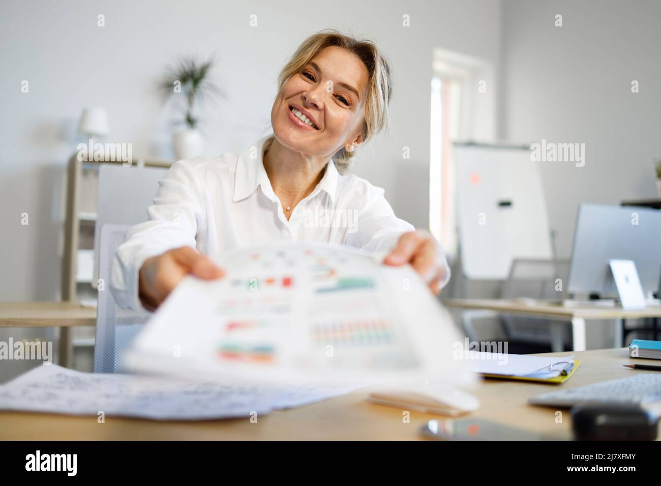 Happy middle aged businesswoman giving papers in office Stock Photo - Alamy