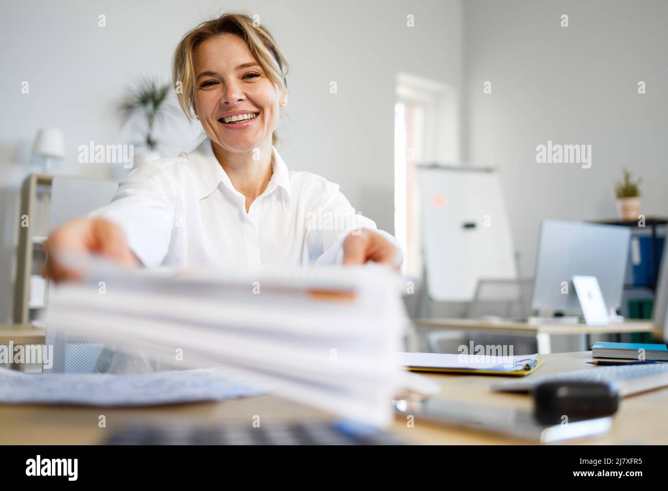 Portrait of cheerful business woman giving document Stock Photo - Alamy