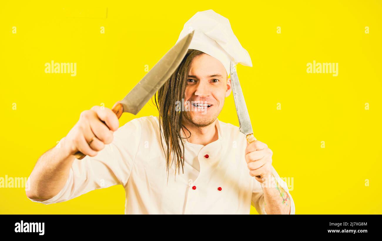 Young insane man dressed as chef with knives on yellow background. Male ...