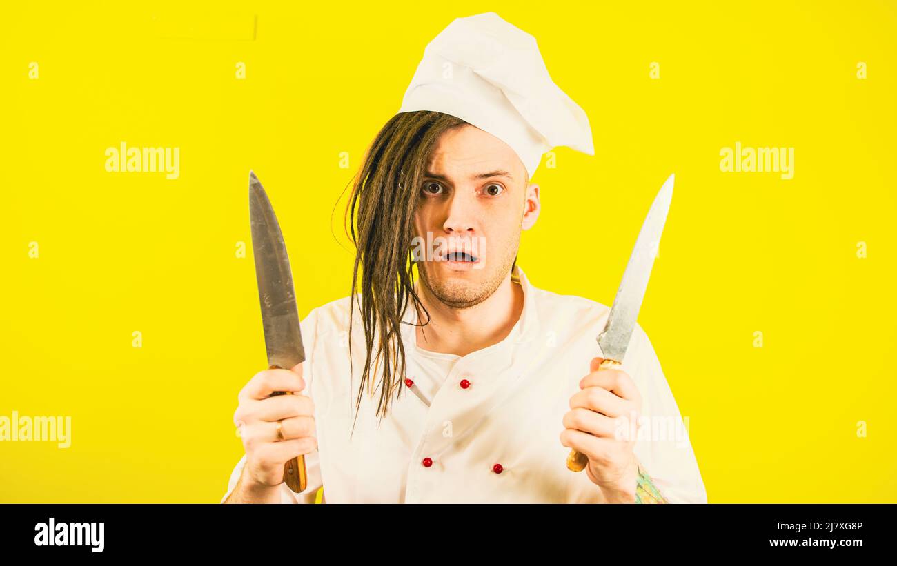 Young man dressed as chef with knives on yellow background. Male cook ...