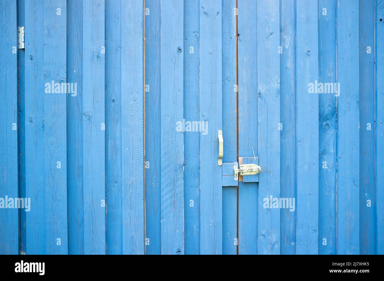 Wooden gate made of boards painted blue, closed with a latch. Copy ...