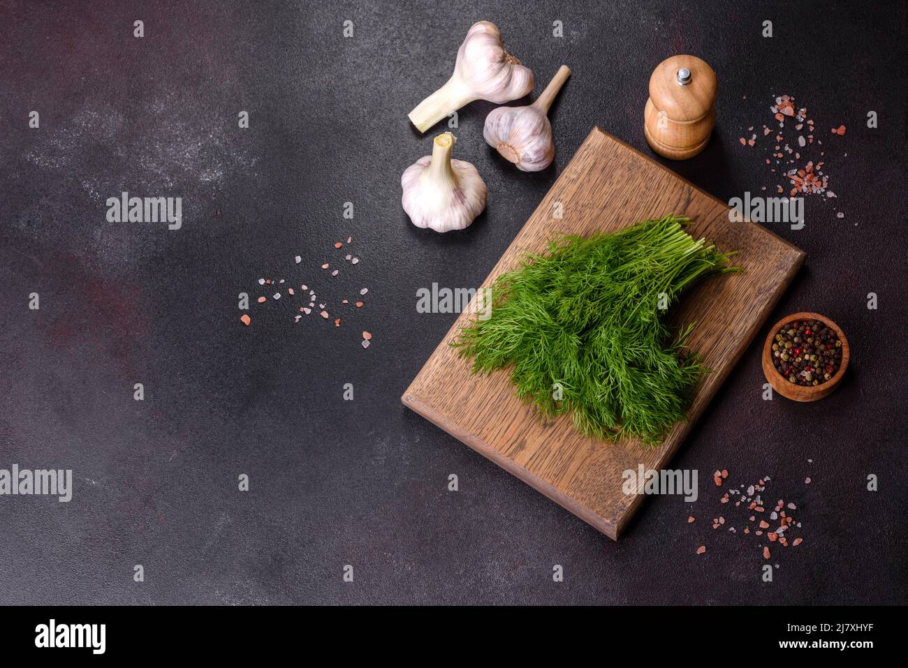 A bunch of fresh green dill on a wooden cutting board on a dark ...