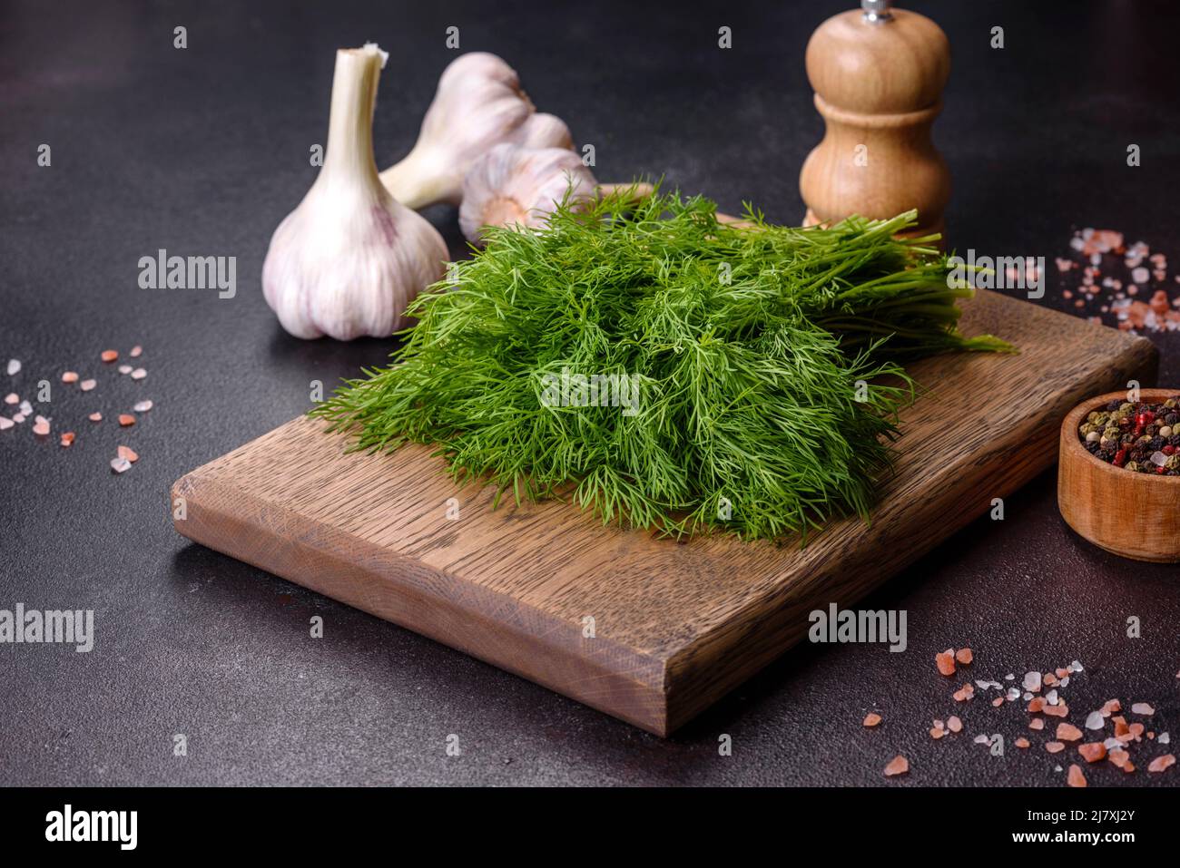 A bunch of fresh green dill on a wooden cutting board on a dark ...