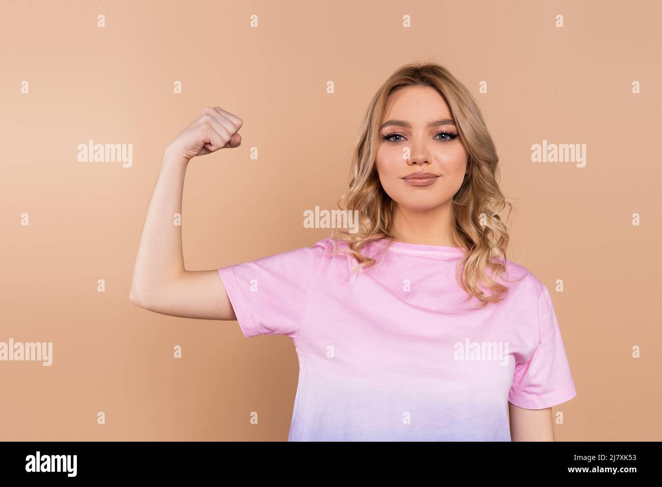 positive woman demonstrating power while looking at camera isolated on ...