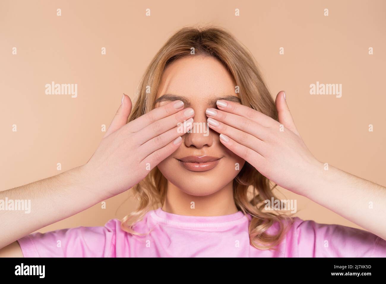 Smiling young woman covering eyes hands hi-res stock photography and ...