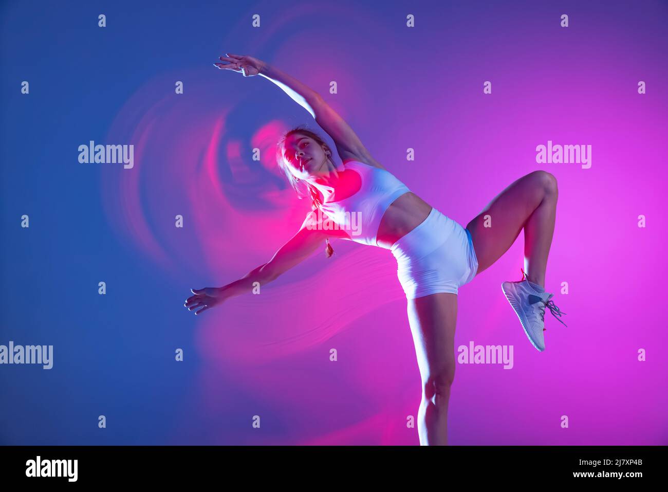 Professional female athlete, runner training isolated on blue studio ...