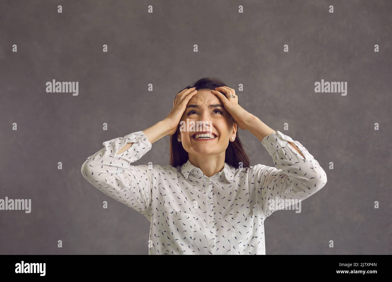 Unhappy crazy woman standing on a gray background screams and cries ...