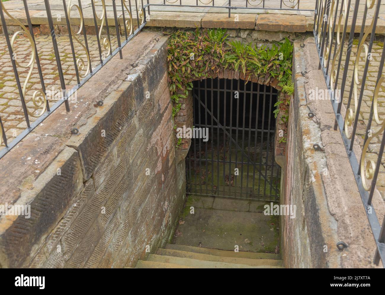 Looking down some old stone steps at a gate made of metal leading ...