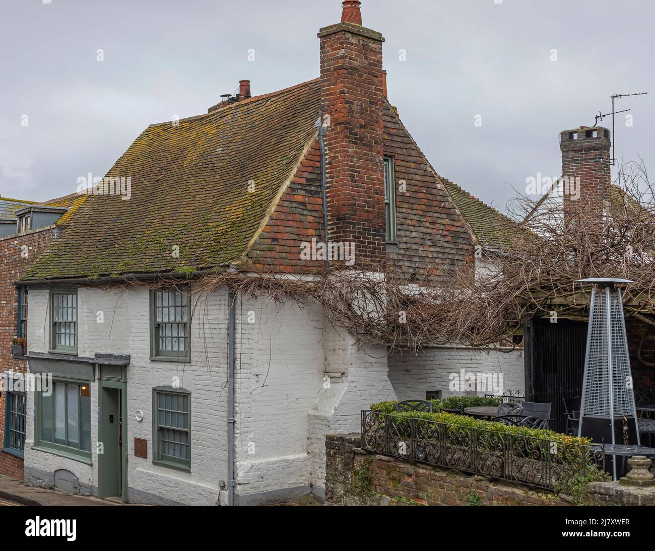 Old traditionl British house with a moss covered roof which is painted ...