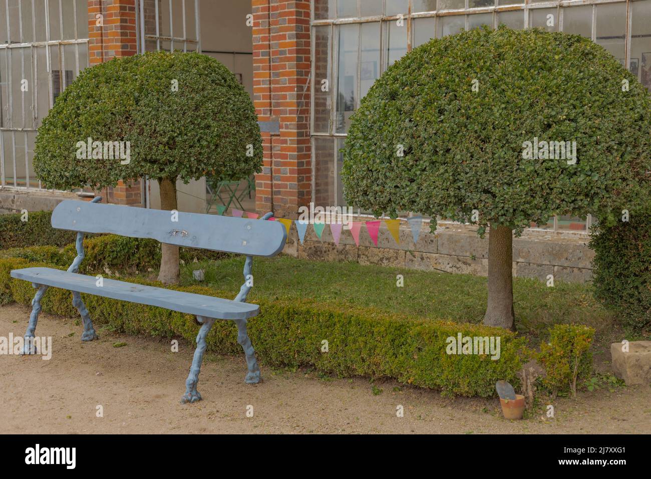 A old blue painted bench next to some trees with multi coloured bunting ...