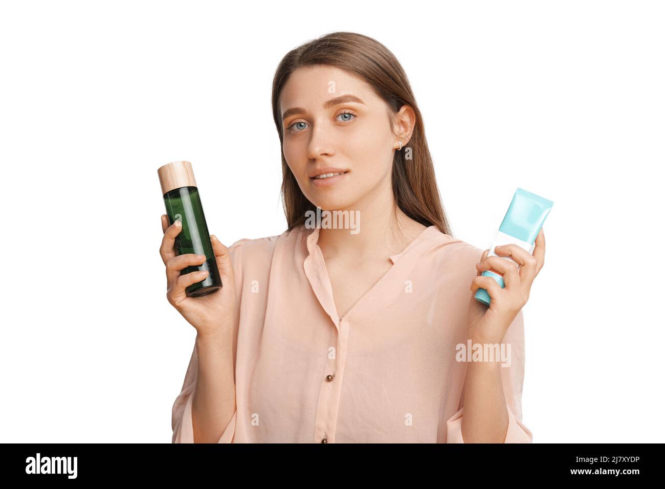 Beautiful woman is holding toner and cream tube while looking at the ...
