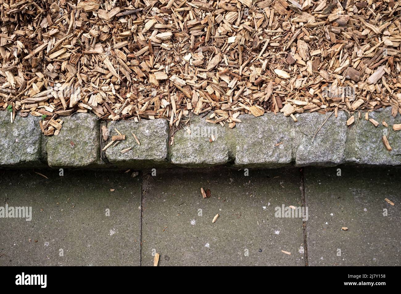 Border stone separates the lawn covered with wood chips and the ...
