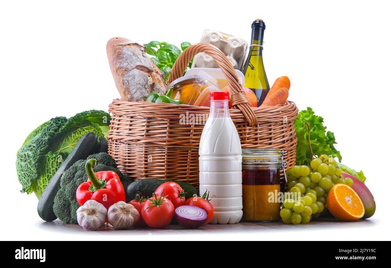 Wicker basket with assorted grocery products including fresh vegetables ...