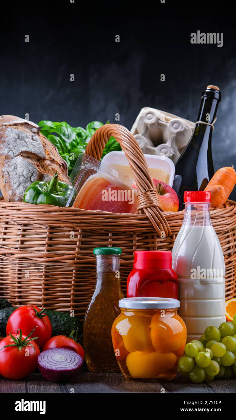 Wicker basket with assorted grocery products including fresh vegetables ...