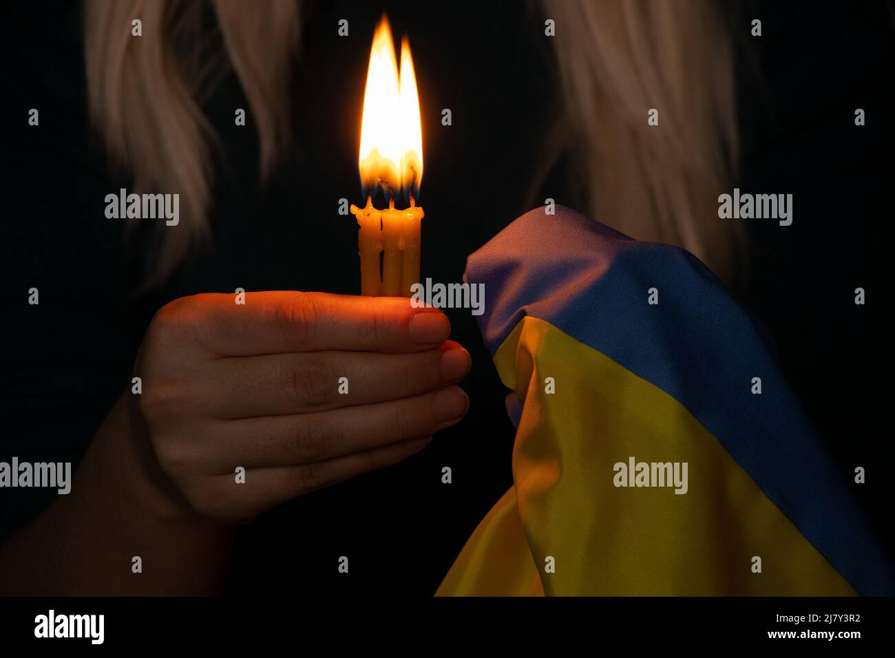 The girl is praying for Ukraine and holding the flag of Ukraine, war in ...