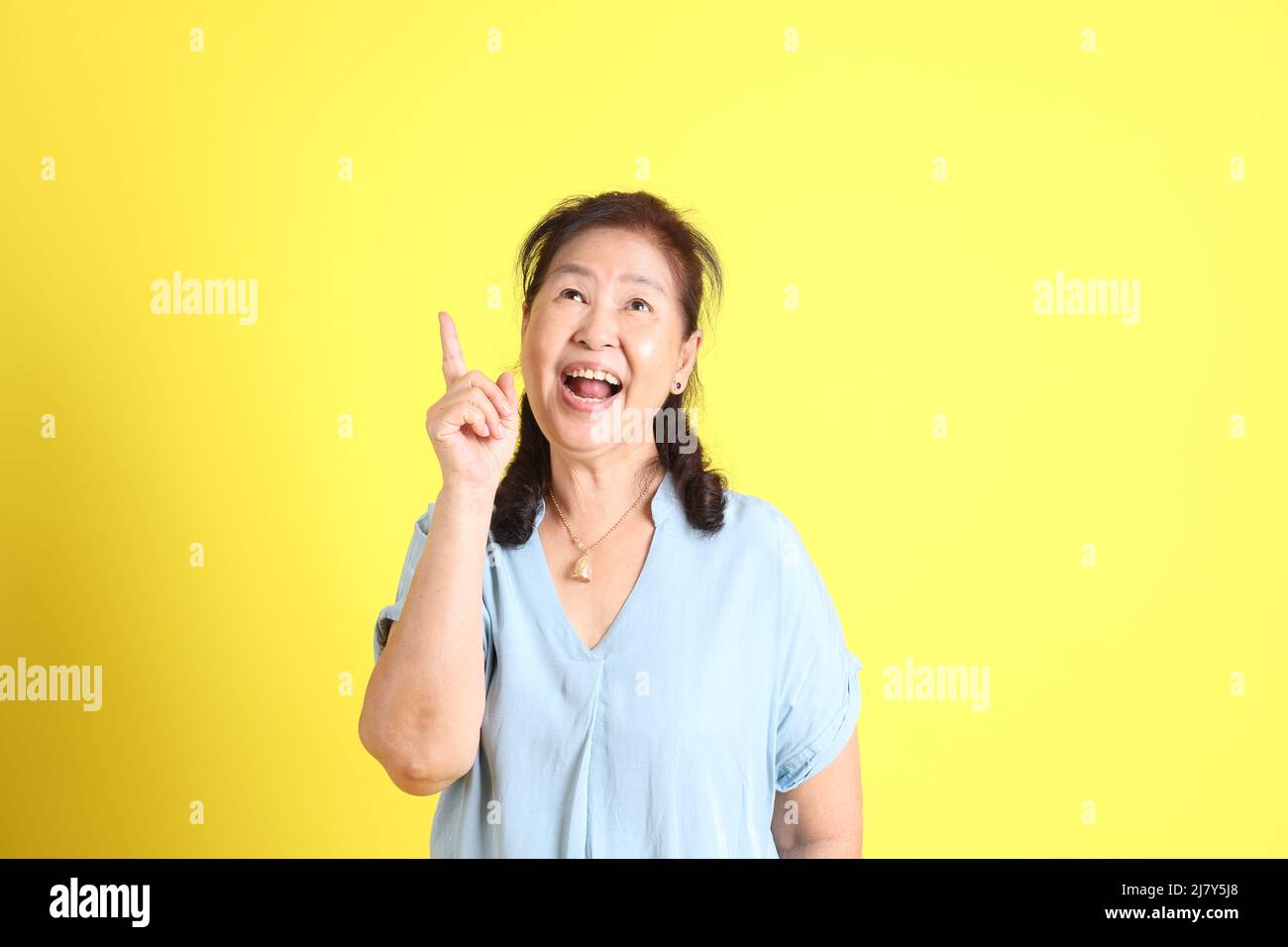 The Asian senior woman wearing light blue shirt standing on the yellow ...
