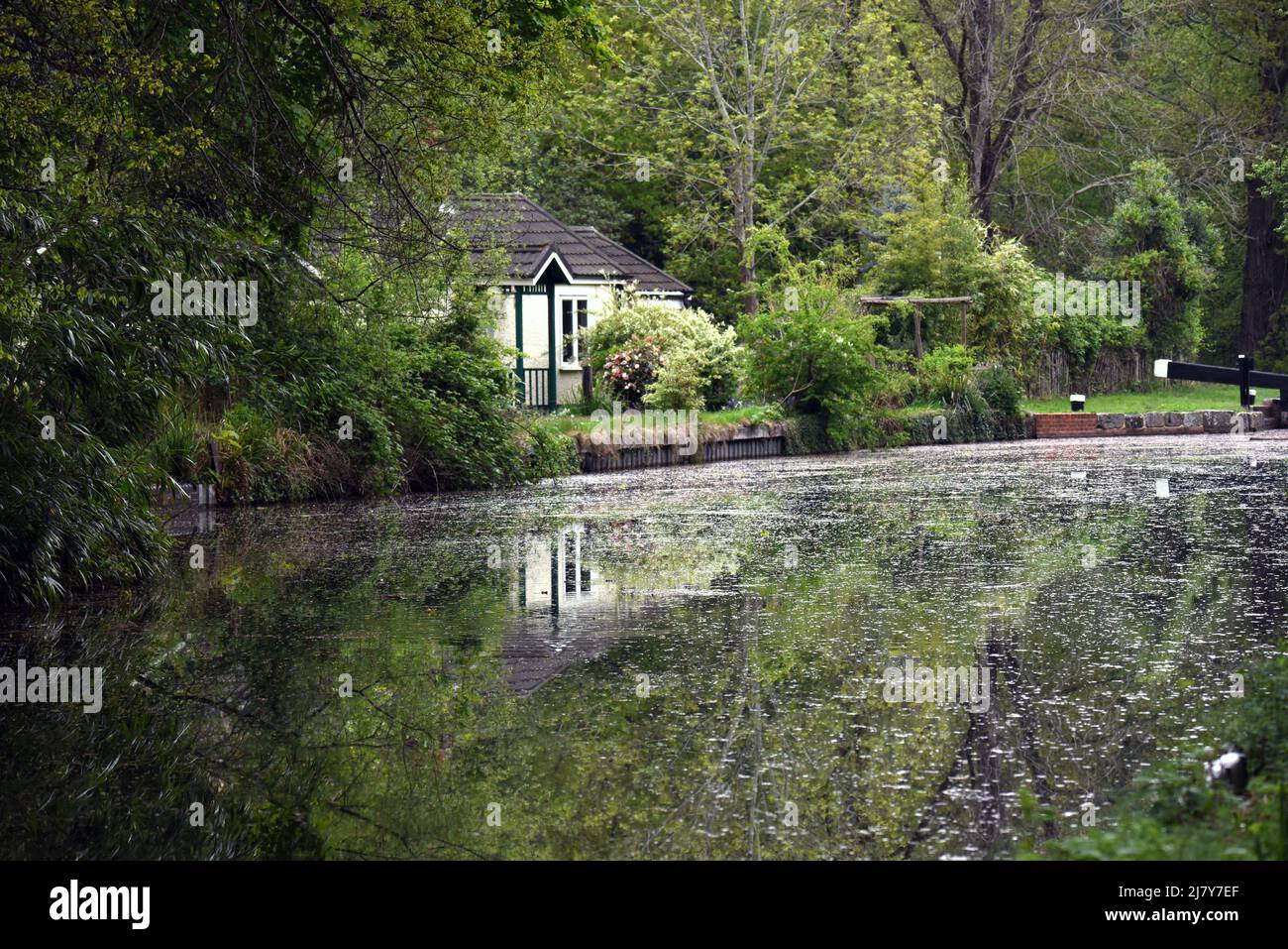 An old canal cottage reflected in the still waters of the beautiful ...