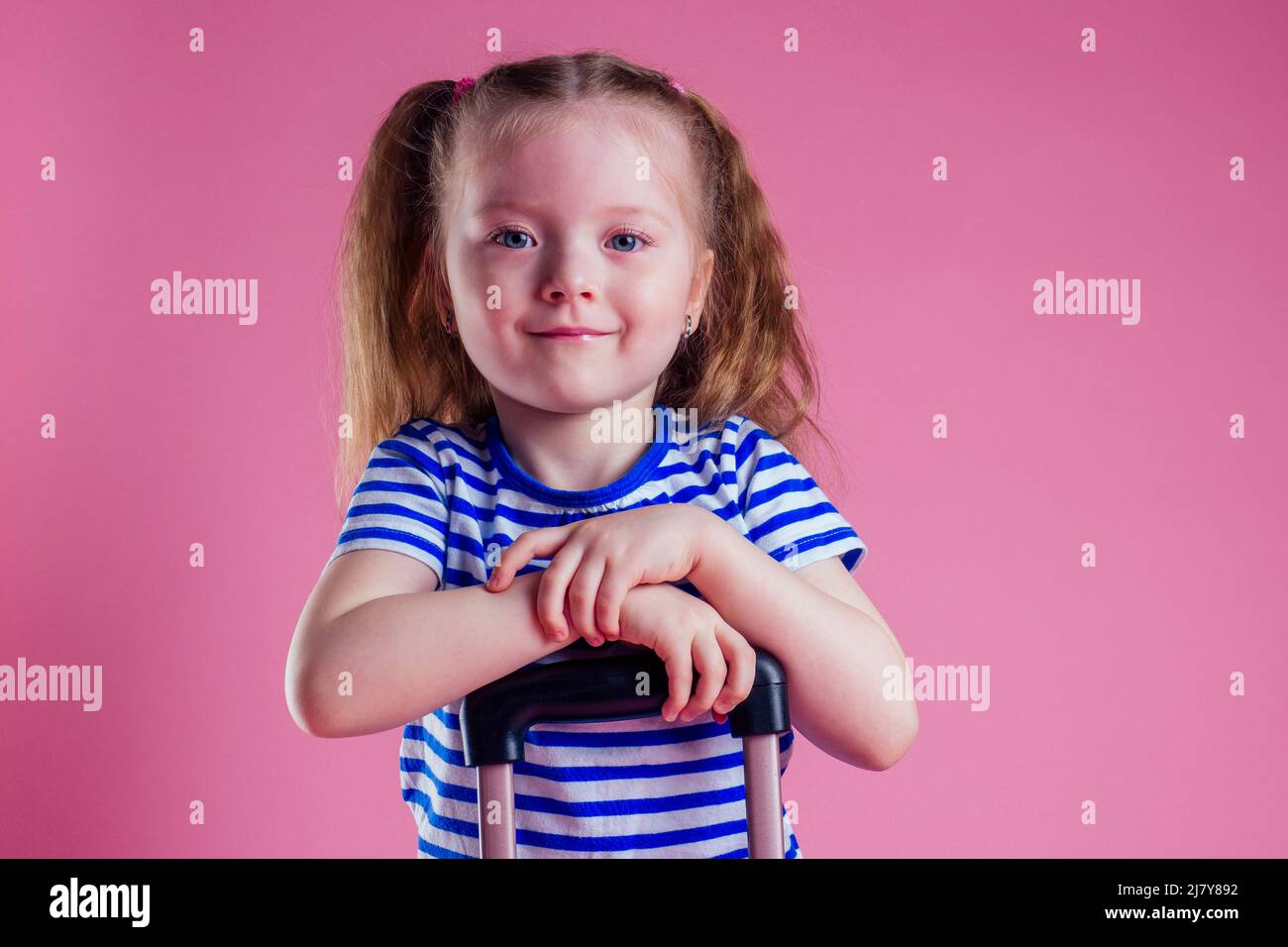 female child striped blue white t-shirt sitting on a large travel ...