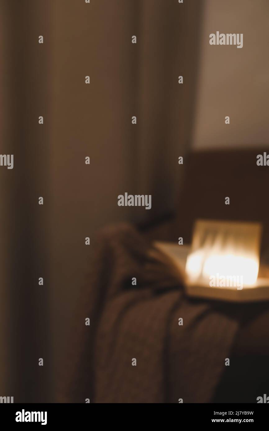 Cozy warm aesthetic evening atmosphere with an open book and plaid ...