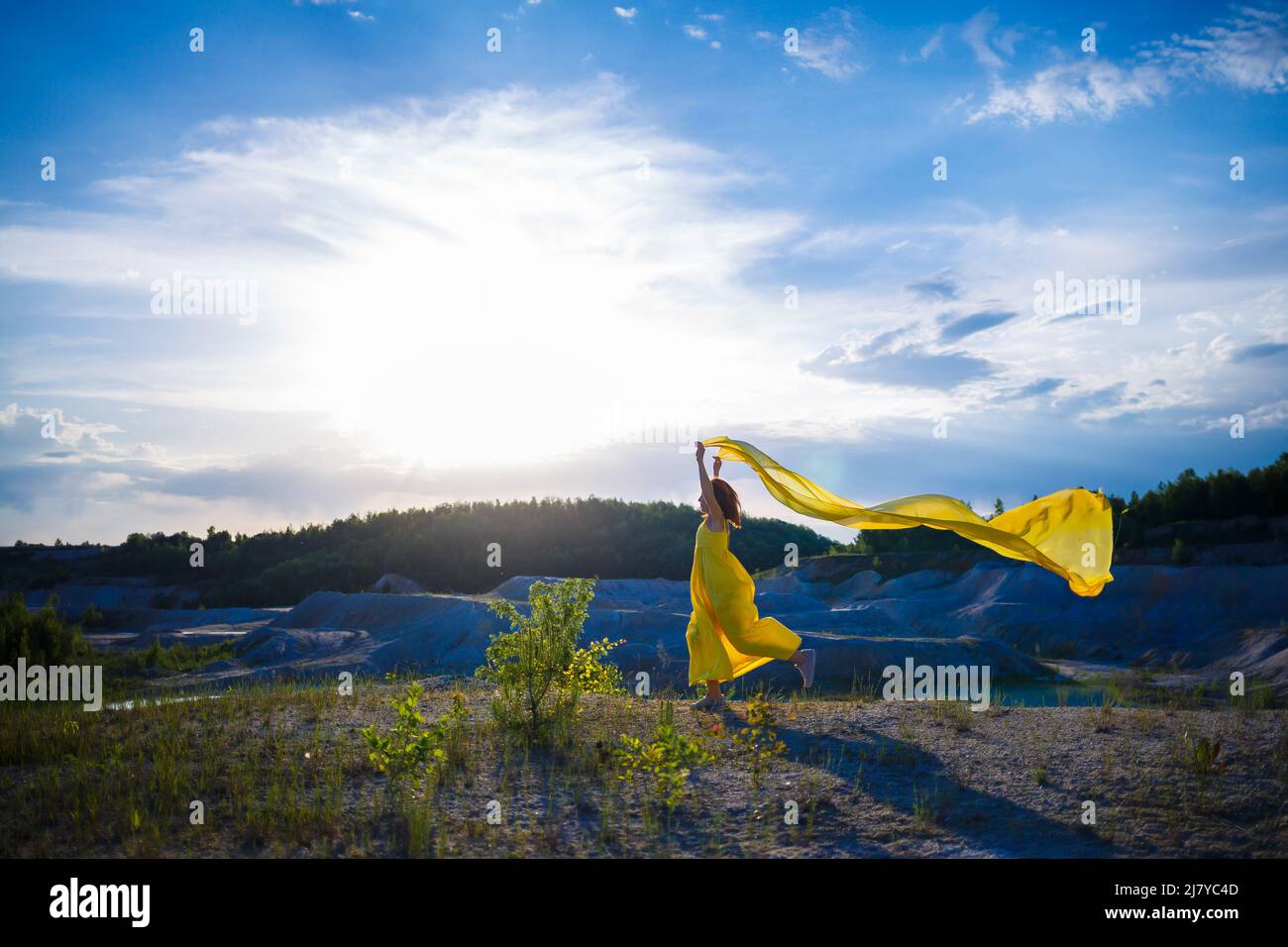 Happy Ukrainian woman running in nature. In a long yellow dress. Symbol ...