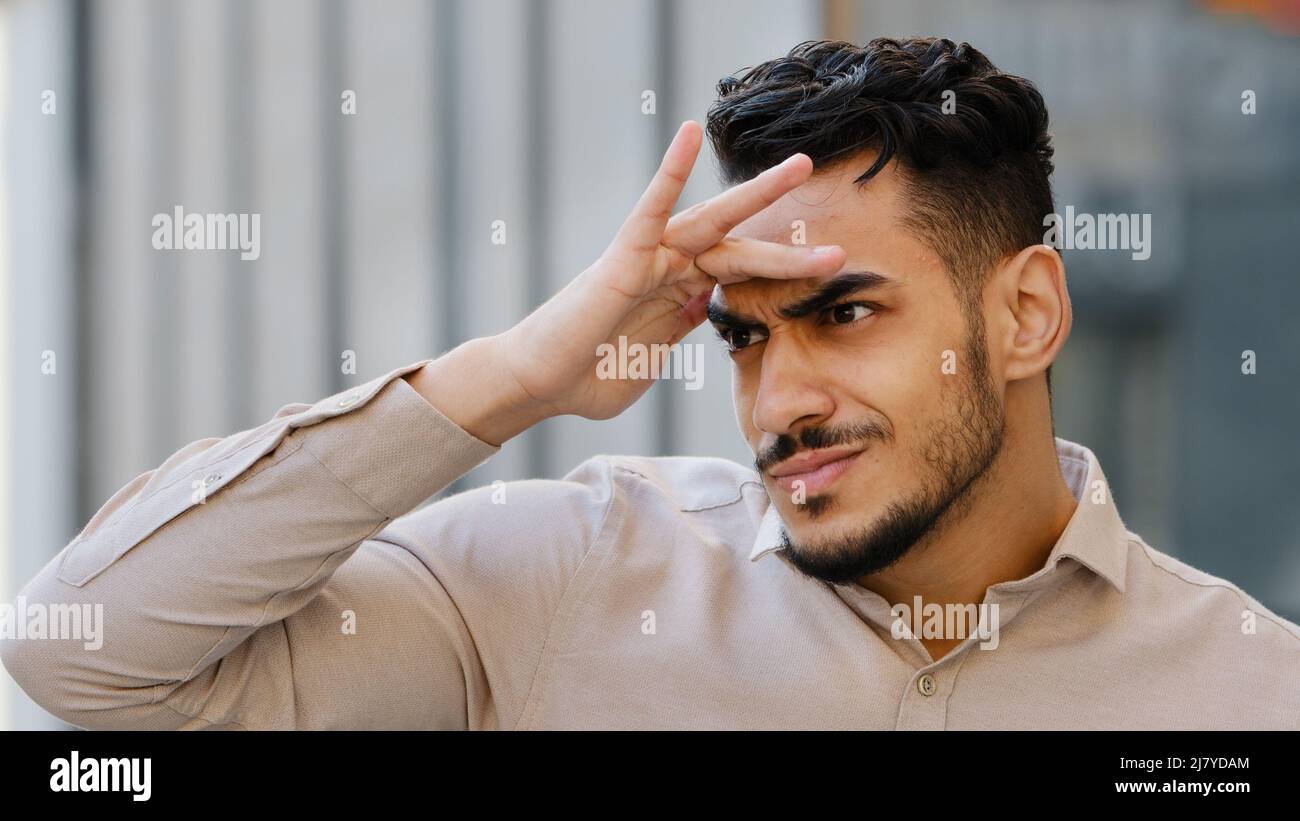 Close-up male suspicious face portrait outdoors in city spy bearded guy ...