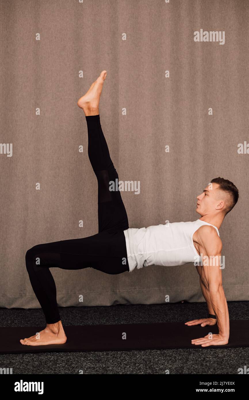 A handsome male athlete performs a workout and lifts his leg up Stock ...
