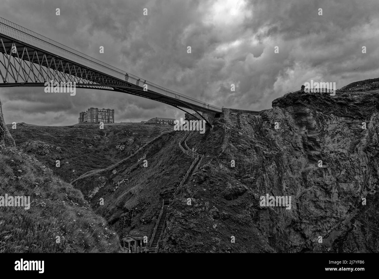 Dramatic Picture Of A Bridge Between To Cliffs From Below Into A Cloudy Sky Taken At Tintagel