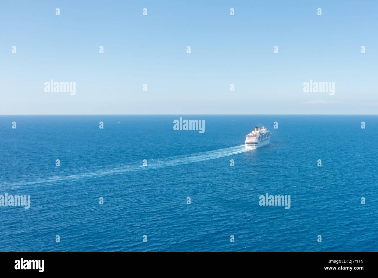 Cruise ship liner sails in the blue sea leaving a plume on the surface ...