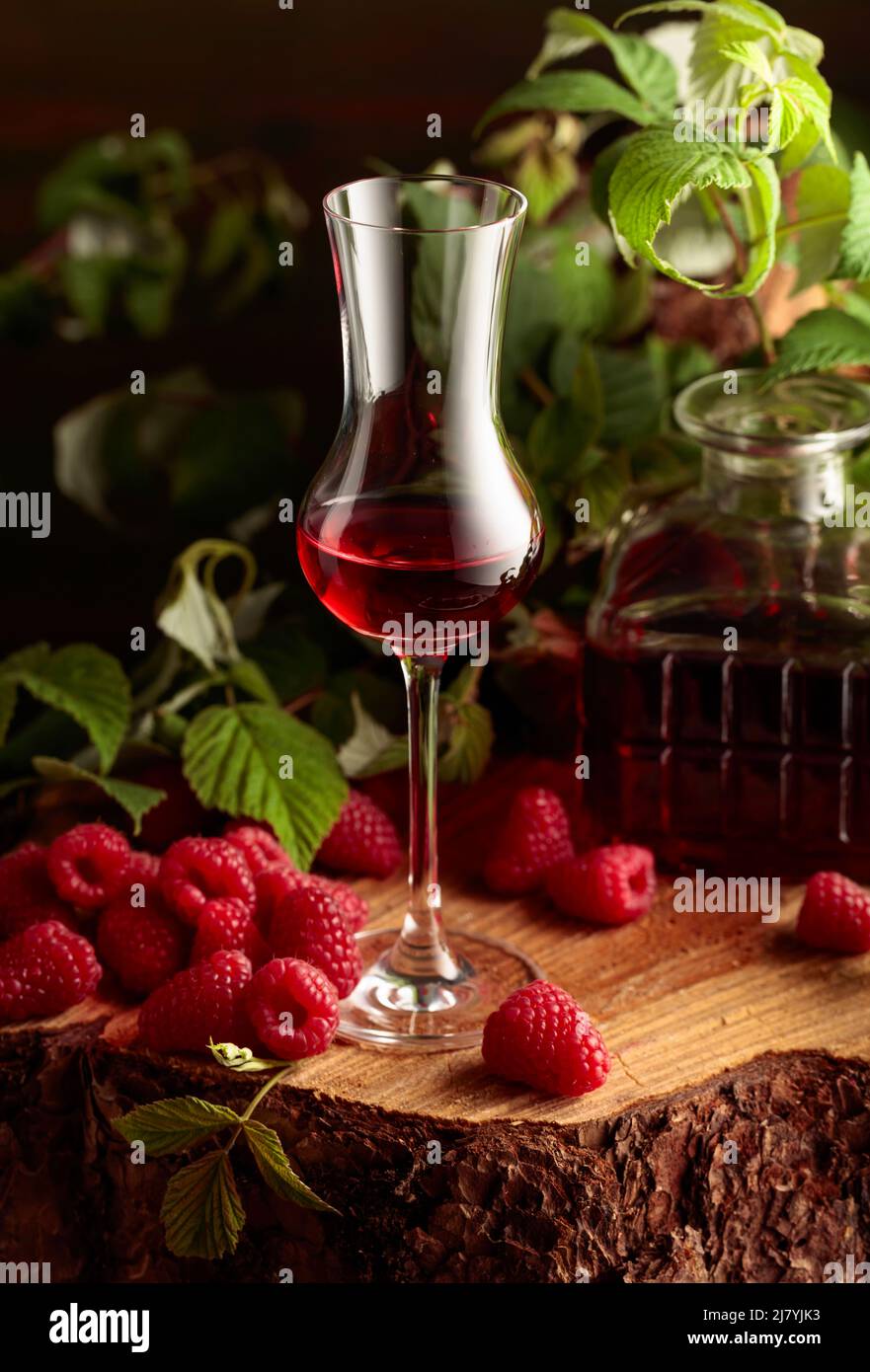 Raspberry liquor and fresh berries with leaves on a pine stump Stock ...